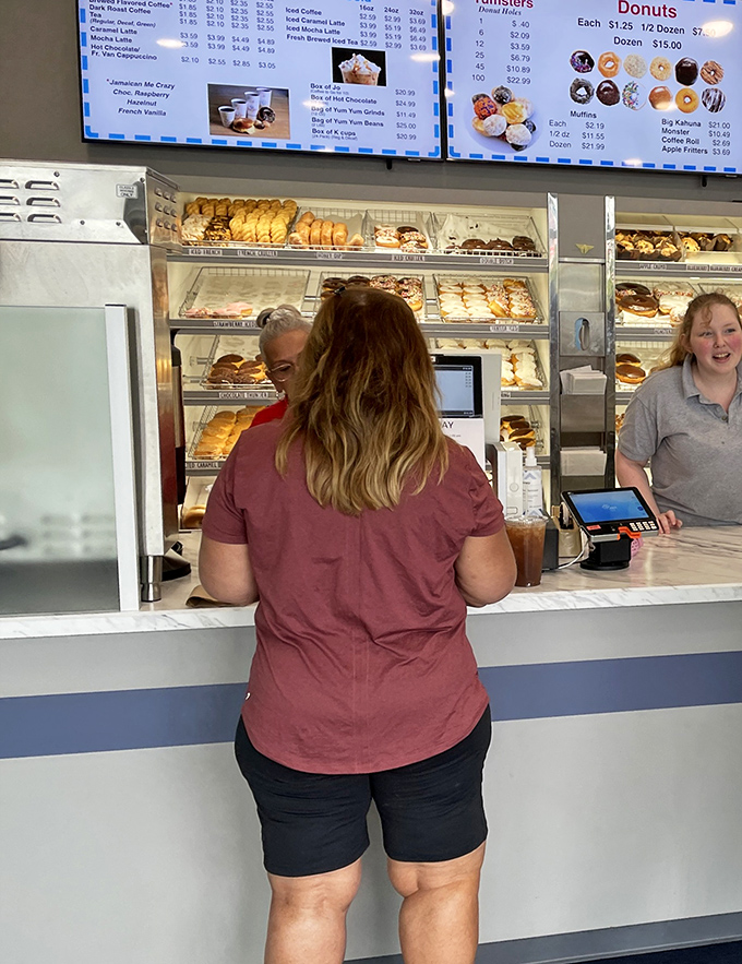 The universal posture of donut contemplation: shoulders slightly hunched, eyes scanning methodically, mind weighing the merits of sprinkles versus glaze.
