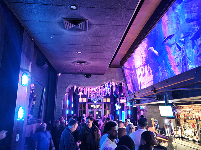 The blue glow bathes everyone in flattering light as patrons gather beneath the aquatic display. Everyone looks 10 years younger in mermaid lighting.
