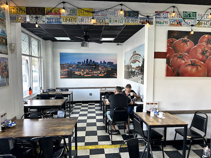License plates and city views adorn white walls above checkerboard floors, creating an atmosphere that says "you're in Kansas City, and you're home."