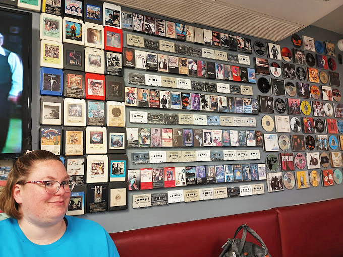 The wall of cassettes and CDs creates a time-traveling jukebox effect, visual proof that good taste extends beyond just what's on your plate.