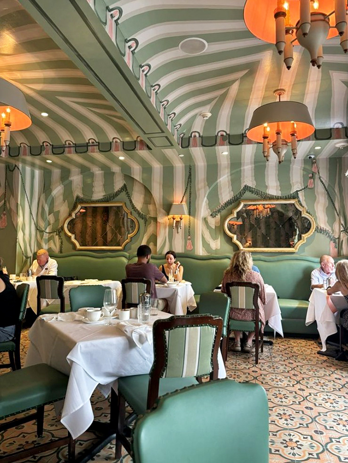 Diners settle into mint-green banquettes, enveloped by striped walls like characters in a delicious play where everyone gets a happy ending.