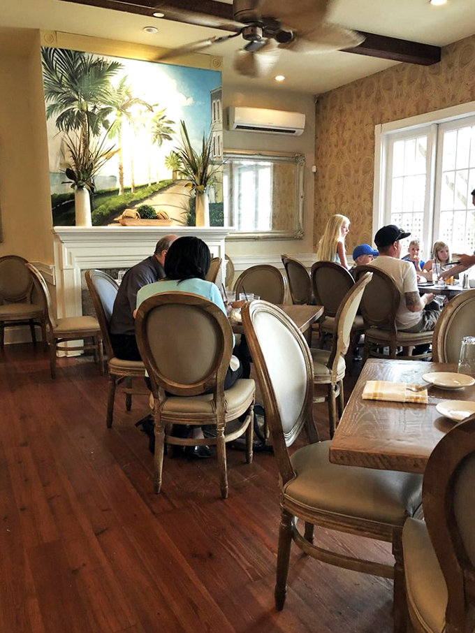 Diners enjoying the warm ambiance beneath a Lowcountry mural. Some restaurants serve food; Poogan's Porch serves experiences.