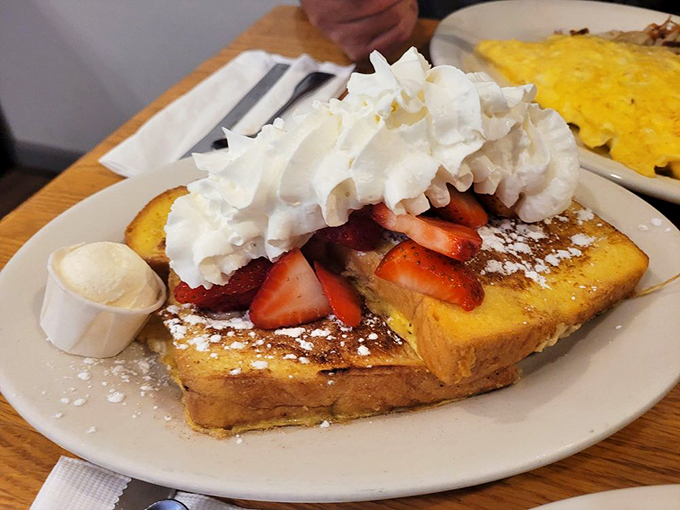 French toast that's transformed into dessert-for-breakfast, with whipped cream mountains and strawberry valleys creating a landscape of morning bliss.