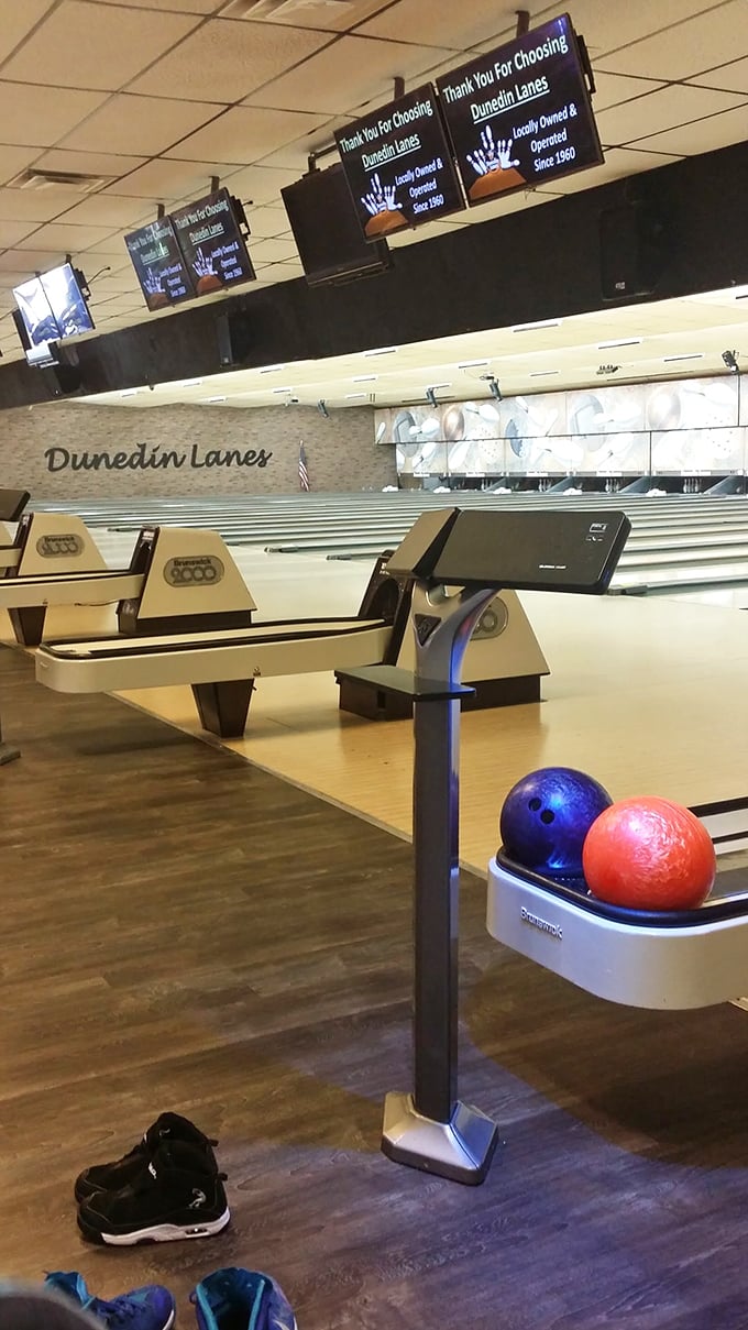 The red and blue bowling balls wait patiently in the return, like old friends ready for another chance to knock down those stubborn remaining pins.
