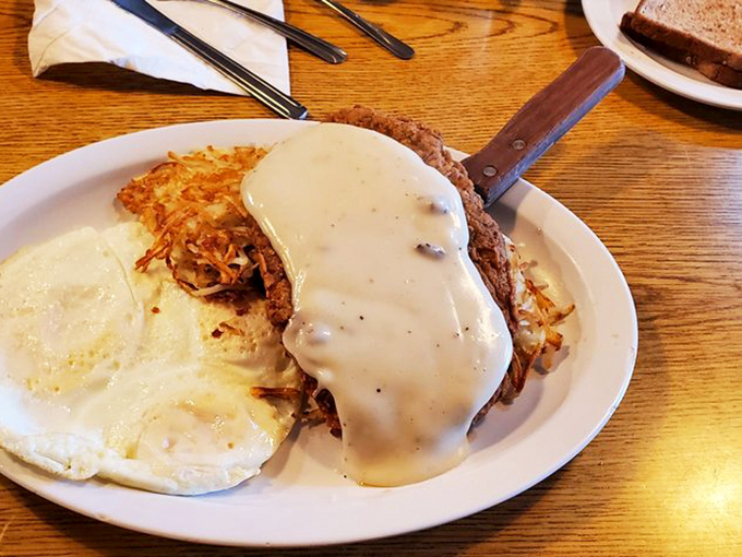 Chicken fried steak swimming in gravy with eggs standing guard &ndash; a breakfast so hearty it requires a nap plan and zero regrets.