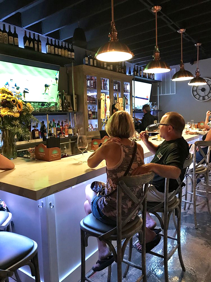 The bar glows with promise as patrons perch on cross-back chairs, sipping wines that have been waiting patiently for this moment.