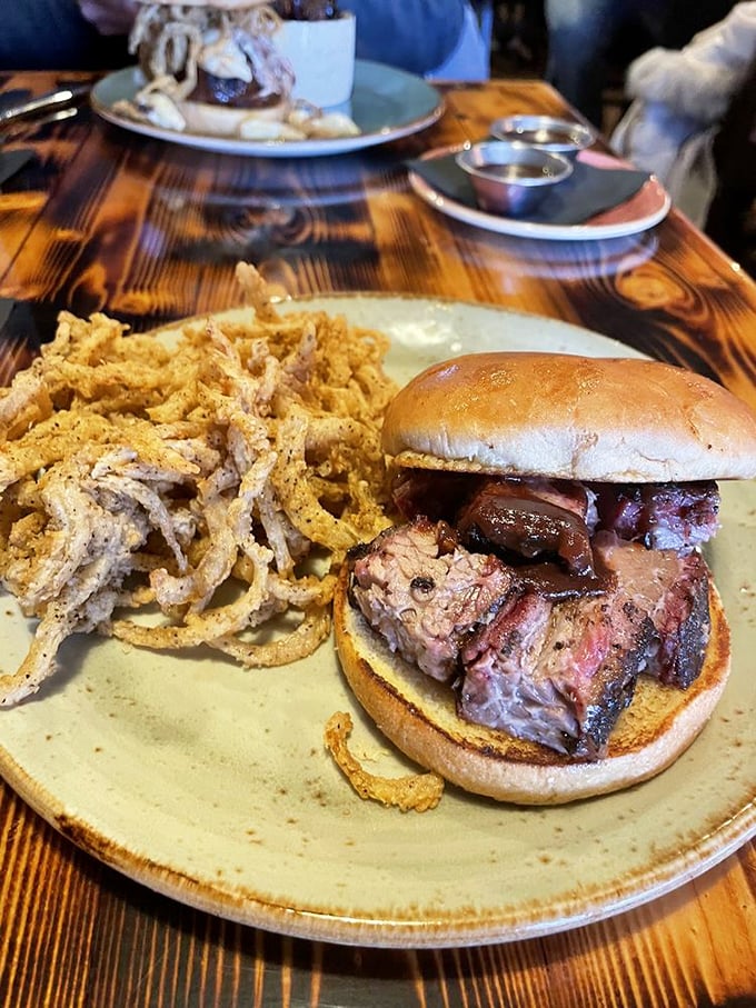 A sandwich that requires both hands and your full attention, with onion straws that crunch like autumn leaves.