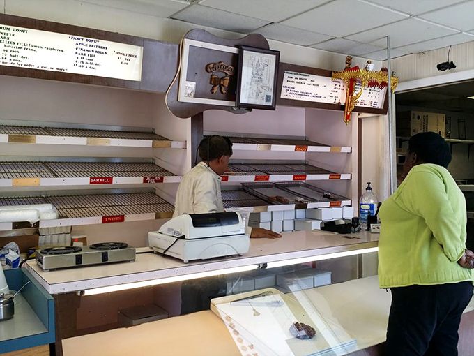 The sacred exchange: customer anticipation meets donut expertise. This moment of transaction is the culmination of early morning baking magic.