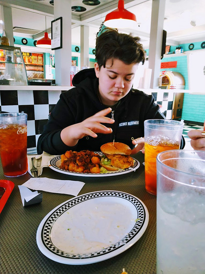 Red pendant lights hanging like cherry earrings above a diner that takes its aesthetic as seriously as its comfort food.