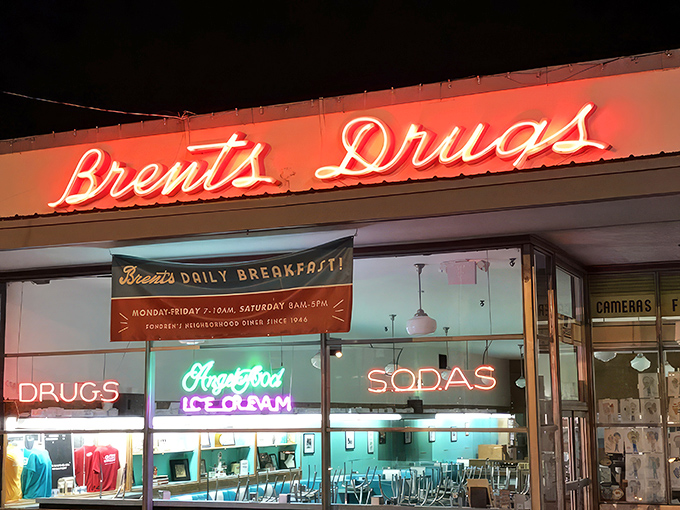 As evening falls, Brent's neon sign transforms from lunch spot to neighborhood landmark, beckoning night owls to The Apothecary for liquid remedies.
