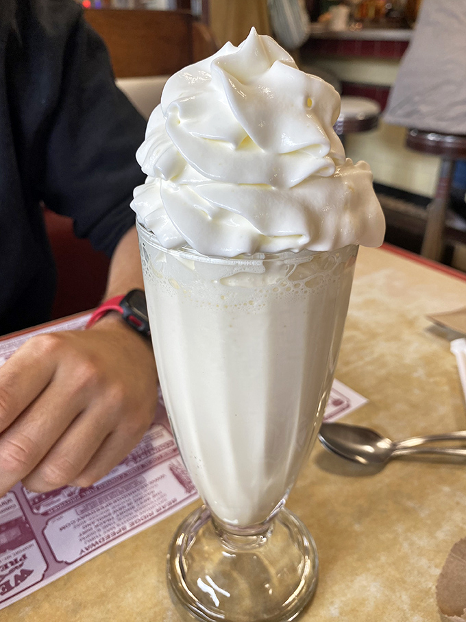 This vanilla milkshake isn't just topped with whipped cream—it's wearing a cloud hat so magnificent it deserves its own weather report.