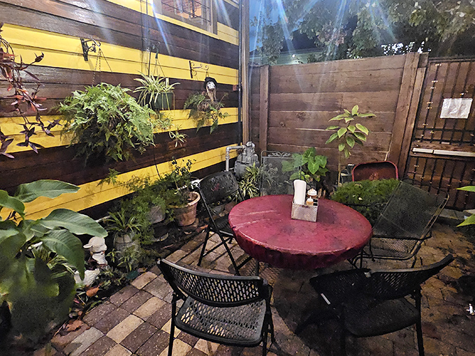 The intimate patio offers a peaceful retreat where the yellow-and-black striped walls remind you that serious barbecue business happens just beyond these plants.