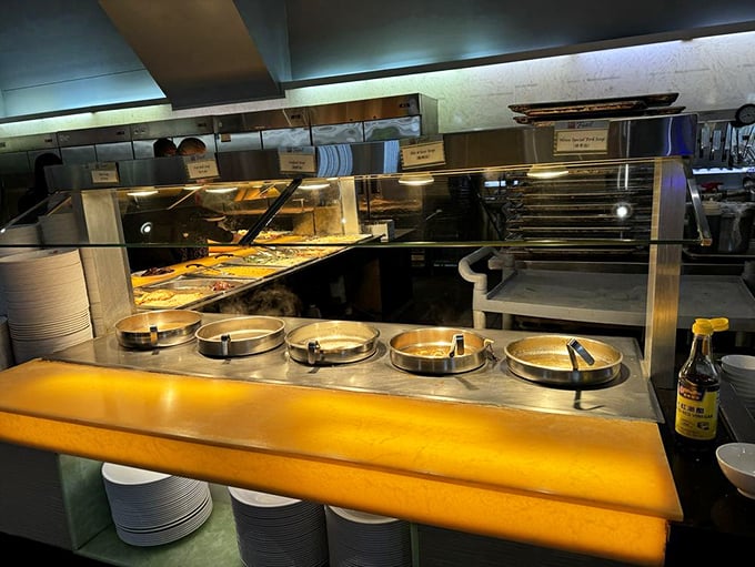 Behind-the-scenes glimpse of the serving area where hot dishes await. The steam rising promises freshness rather than food purgatory.