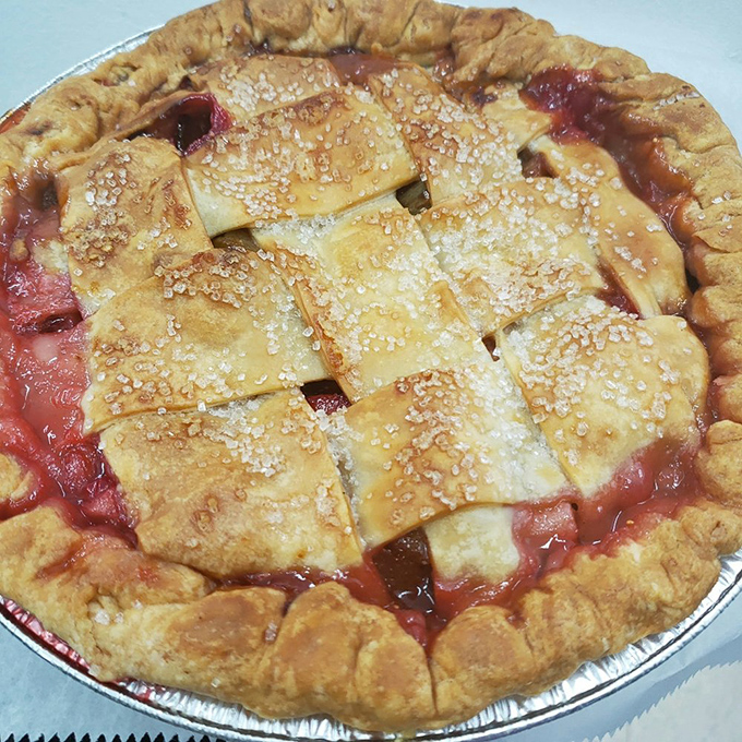 Strawberry rhubarb pie with its crimson filling peaking through golden lattice&mdash;nature's perfect sweet-tart romance in pastry form.