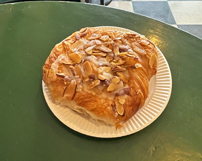 An almond croissant topped with sliced nuts and glaze that belongs in the Louvre, not just on your breakfast plate.
