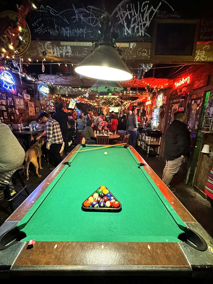 The pool table stands ready while patrons gather in the glow of neon, where strangers become friends over shared chicken and cold drinks.