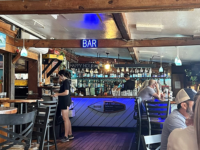 The bar glows with blue light and possibility, where locals and tourists alike find common ground in appreciation of good drinks and sea stories.