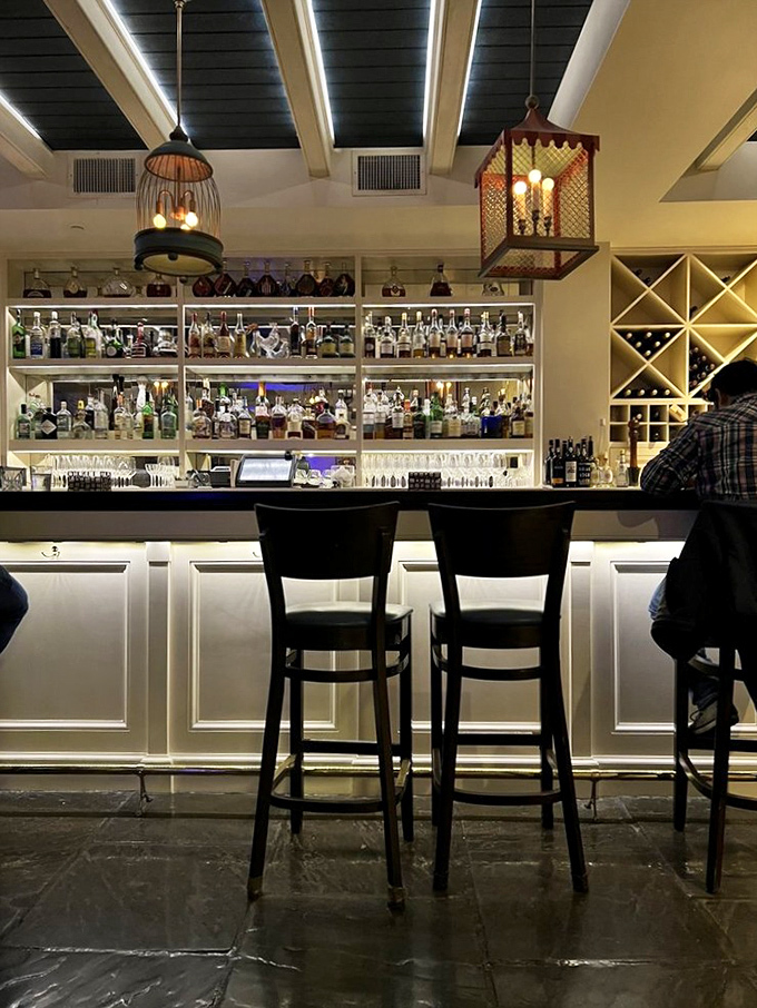 The bar gleams with bottles that promise liquid courage, sophisticated conversation, and possibly that second dessert you're debating.