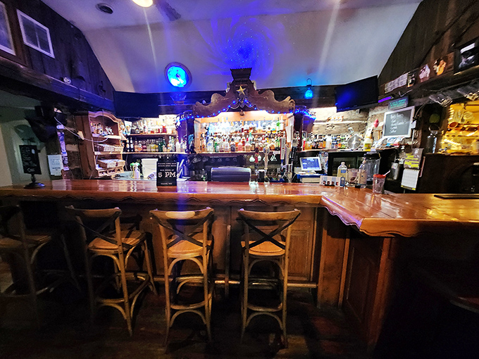 The bar area transforms into an evening oasis, where wooden stools await patrons ready to swap stories beneath the glow of blue lights.