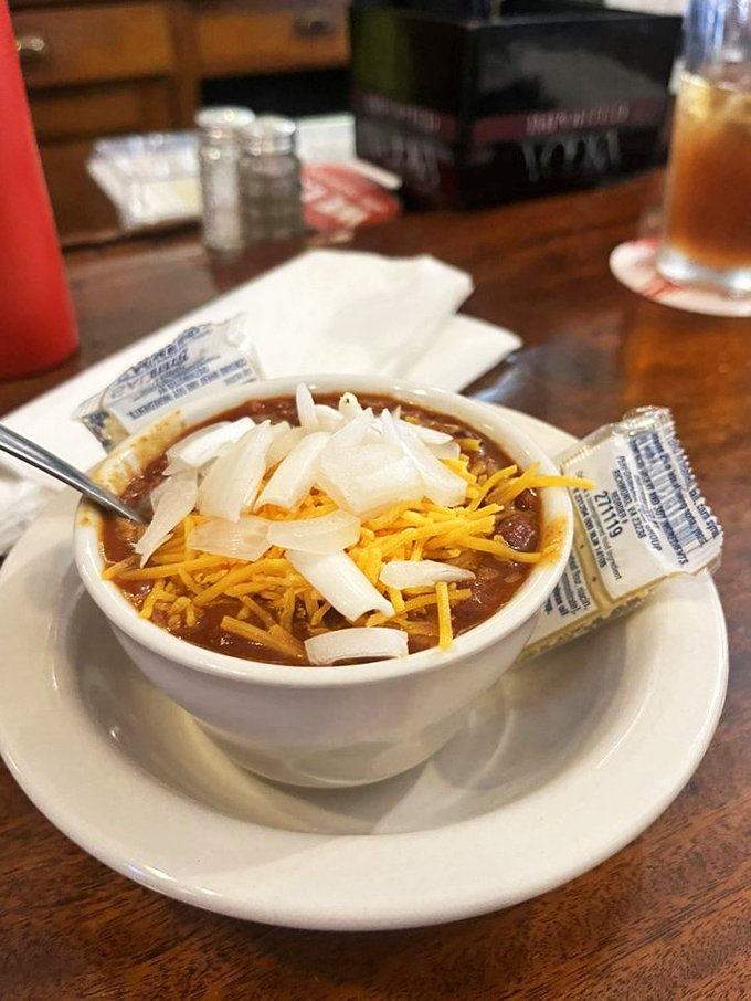 A bowl of chili topped with sharp cheddar and onions—the kind of hearty, soul-warming dish that makes Midwestern winters not just bearable, but welcome.