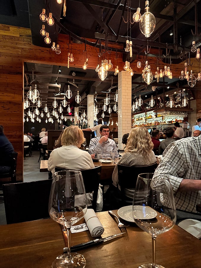 The warm glow of conversation flows as freely as the wine beneath a constellation of Edison bulbs. Dining here is a communal experience elevated.