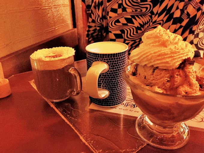 Coffee served in eclectic mugs alongside desserts that look like they escaped from a pastry chef's dream journal.