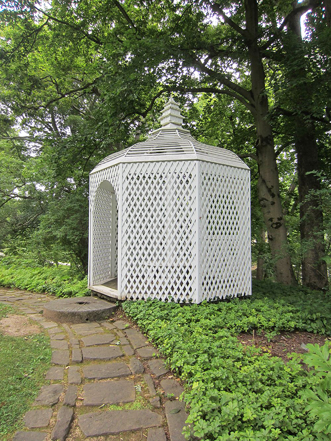 The latticed gazebo stands like a pristine geometric poem amid the garden's free verse. A perfect spot for proposals, profound thoughts, or just pretending you're in a Jane Austen novel.