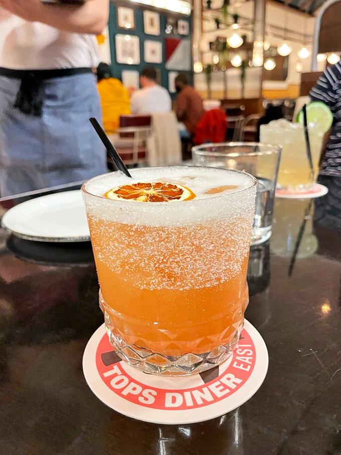 A craft cocktail that's dressed better than most people at brunch. That dehydrated orange garnish is the tiny hat this drink deserves.