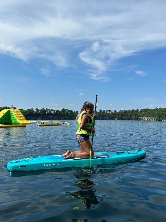 Finding balance in blue paradise. Paddleboarding offers a peaceful alternative to the inflatable chaos, gliding serenely past the park's floating obstacle course.