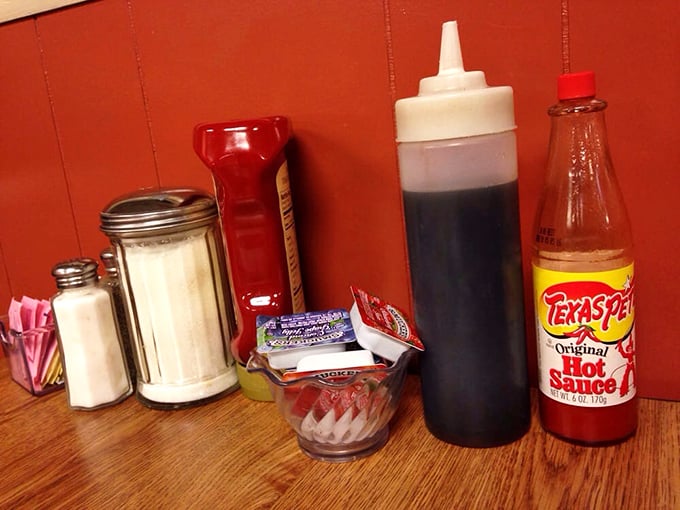 The classic diner table setup: condiments standing at attention, ready to enhance whatever comfort food masterpiece is about to arrive.