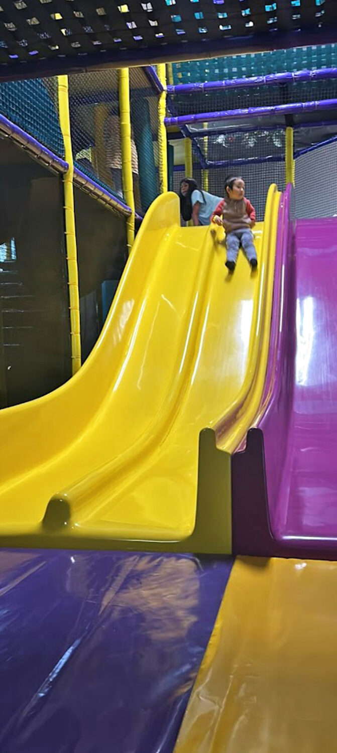 Yellow slides that promise the kind of stomach-dropping joy adults secretly envy while pretending to be "just watching the kids."