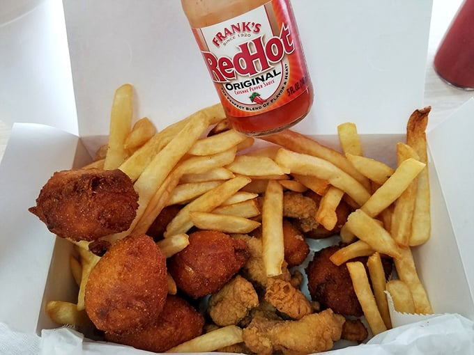 Frank's RedHot sauce stands guard over a treasure chest of golden fries and crispy delights&mdash;proof that sometimes the best condiments know when to let the food shine.