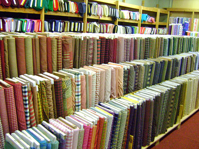 Homespun fabrics stand in perfect formation, a textile library where each bolt tells a different story of potential projects and possibilities.