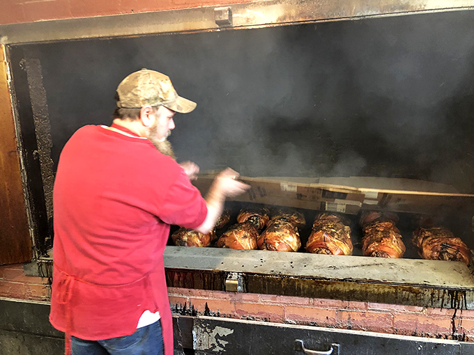 The pitmaster at work, tending to meat with the focused dedication of a symphony conductor. This is where the magic happens.