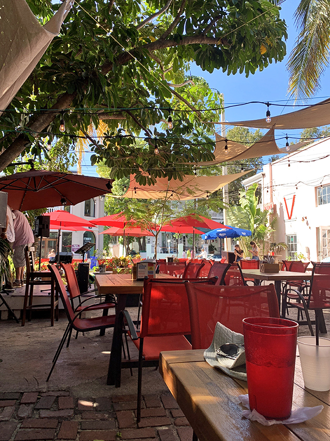 Dappled sunlight filters through canvas sails and tropical foliage in the outdoor seating area, where every table feels like you've discovered a secret garden.