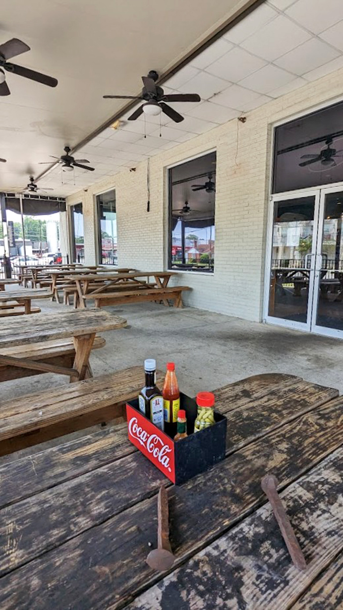 The outdoor seating area offers rustic wooden tables, ceiling fans for those humid Alabama days, and condiment caddies ready for whatever you're craving.