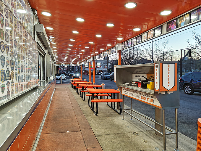 The outdoor seating area offers front-row tickets to the South Philly street theater, with orange tables that match the establishment's vibrant personality.