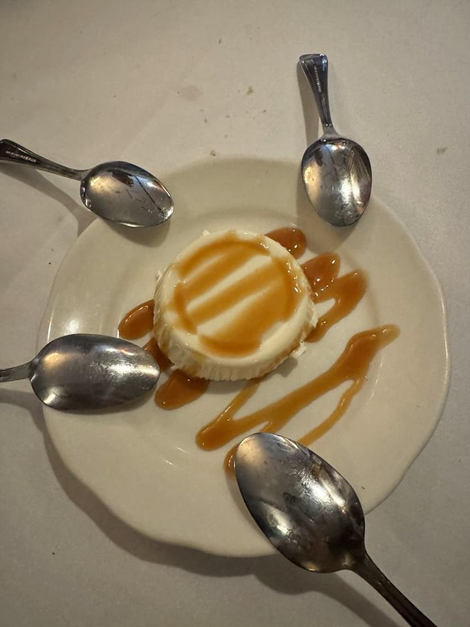 Panna cotta surrounded by spoons like planets orbiting the sun. That caramel sauce is about to create a gravitational pull toward pure happiness.