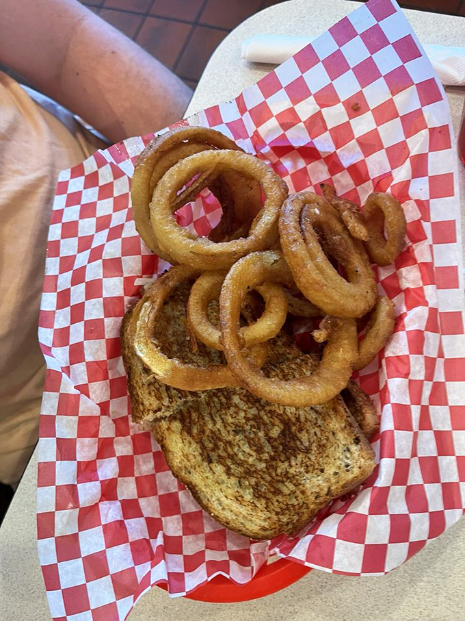 Onion rings perched atop grilled bread like golden halos of flavor. This sandwich isn't just lunch&mdash;it's a midday celebration on a plate.