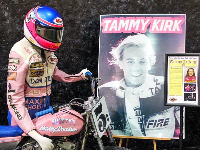 Tammy Kirk broke barriers on two wheels, her pink racing suit as revolutionary as her talent. This display honors motorsport pioneers who refused to stay in designated lanes.