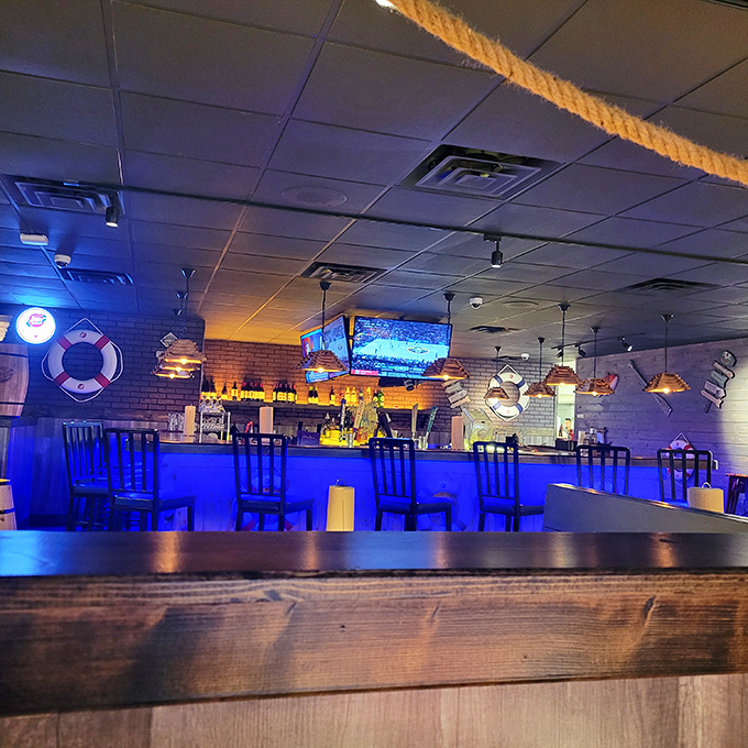 The bar area glows with blue light and nautical charm. Life preservers on the wall remind you: calories don't count during seafood adventures.