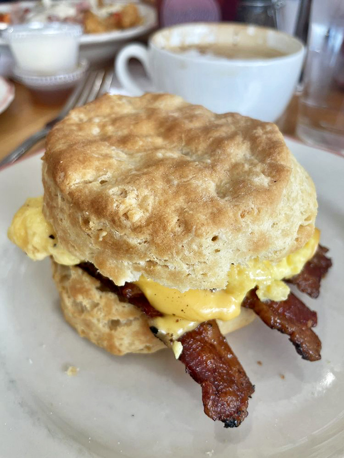 The classic breakfast sandwich—where a golden biscuit cradles eggs, cheese, and bacon like precious cargo on a delicious journey.