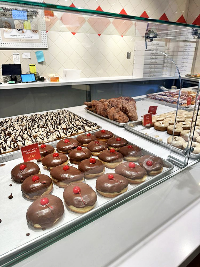 The counter stretches like a runway for donut fashion week, each tray showcasing collections that would make any pastry chef proud.