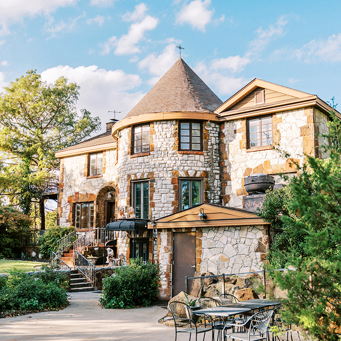 The castle reveals itself through the trees, its stone facade glowing in the afternoon light like a European postcard come to life.