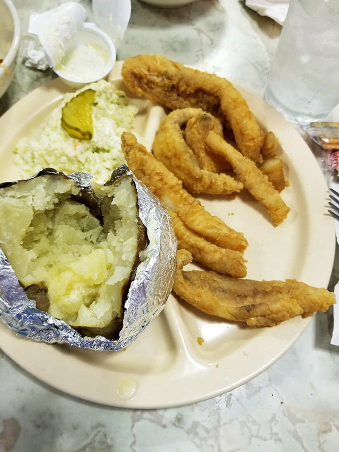 The classic fish camp trio: perfectly fried flounder, a pickle-topped coleslaw, and a steaming baked potato. Simple perfection on a plate.