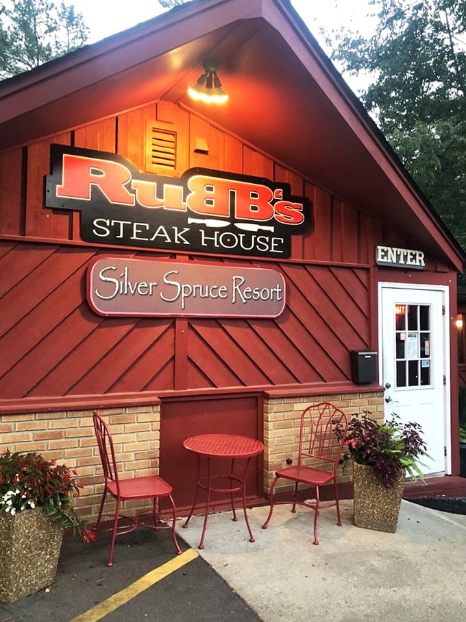 The charming entrance with its red outdoor furniture invites you to linger a moment before stepping into culinary bliss.