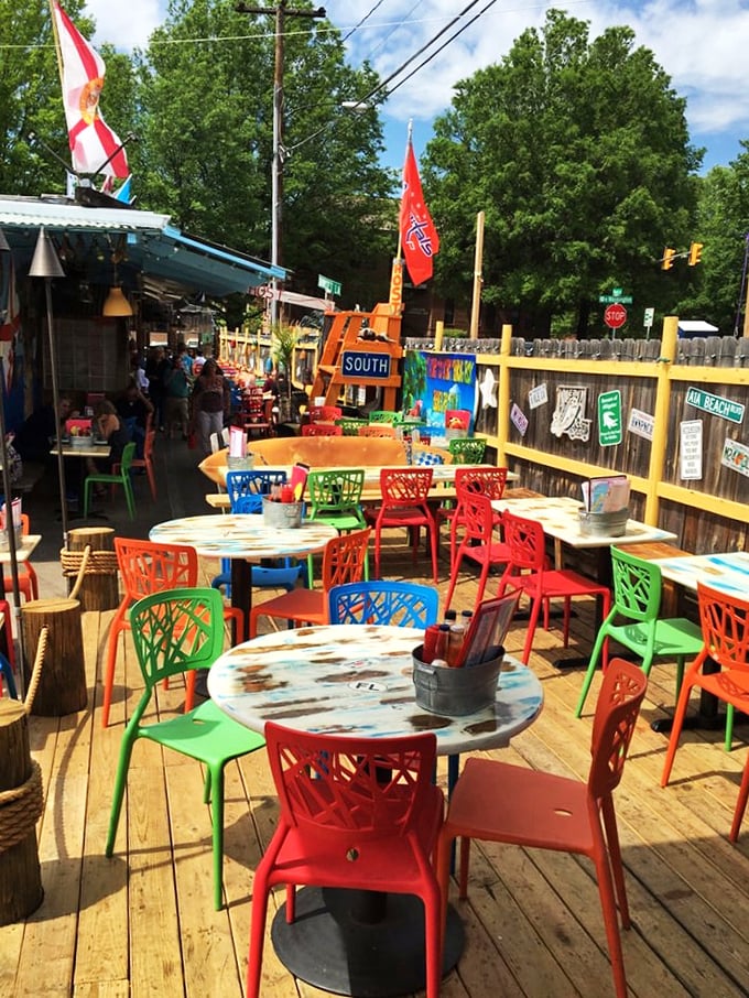 The outdoor patio brings the beach shack experience into the sunshine. Colorful chairs, weathered tables, and the promise of escape.