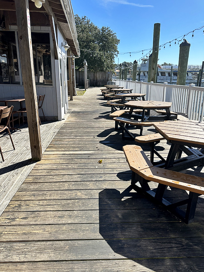 Morning sunlight bathes the weathered deck in golden warmth&mdash;empty tables patiently waiting for the day's seafood pilgrims to arrive.
