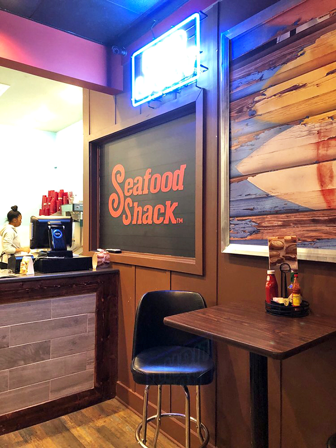 The Seafood Shack sign glows like a beacon for hungry travelers. That weathered wood wall behind it whispers tales of distant shores.