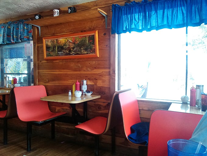 Red booth seating against wooden walls with blue curtains&mdash;the kind of corner table where locals have celebrated birthdays, anniversaries, and Tuesday specials since forever.